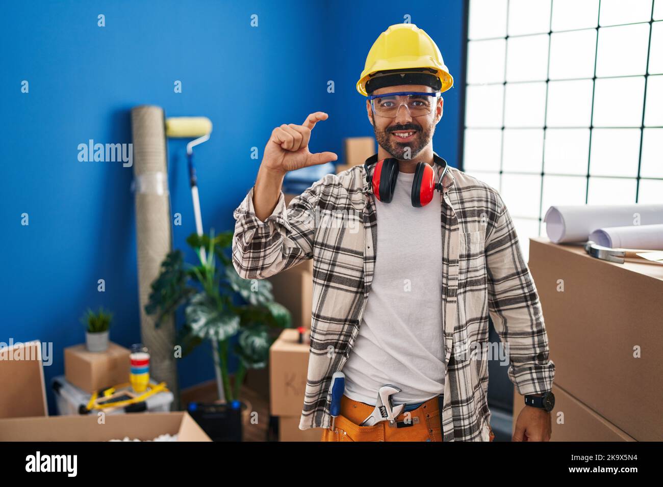 Young hispanic man with beard working at home renovation smiling and ...