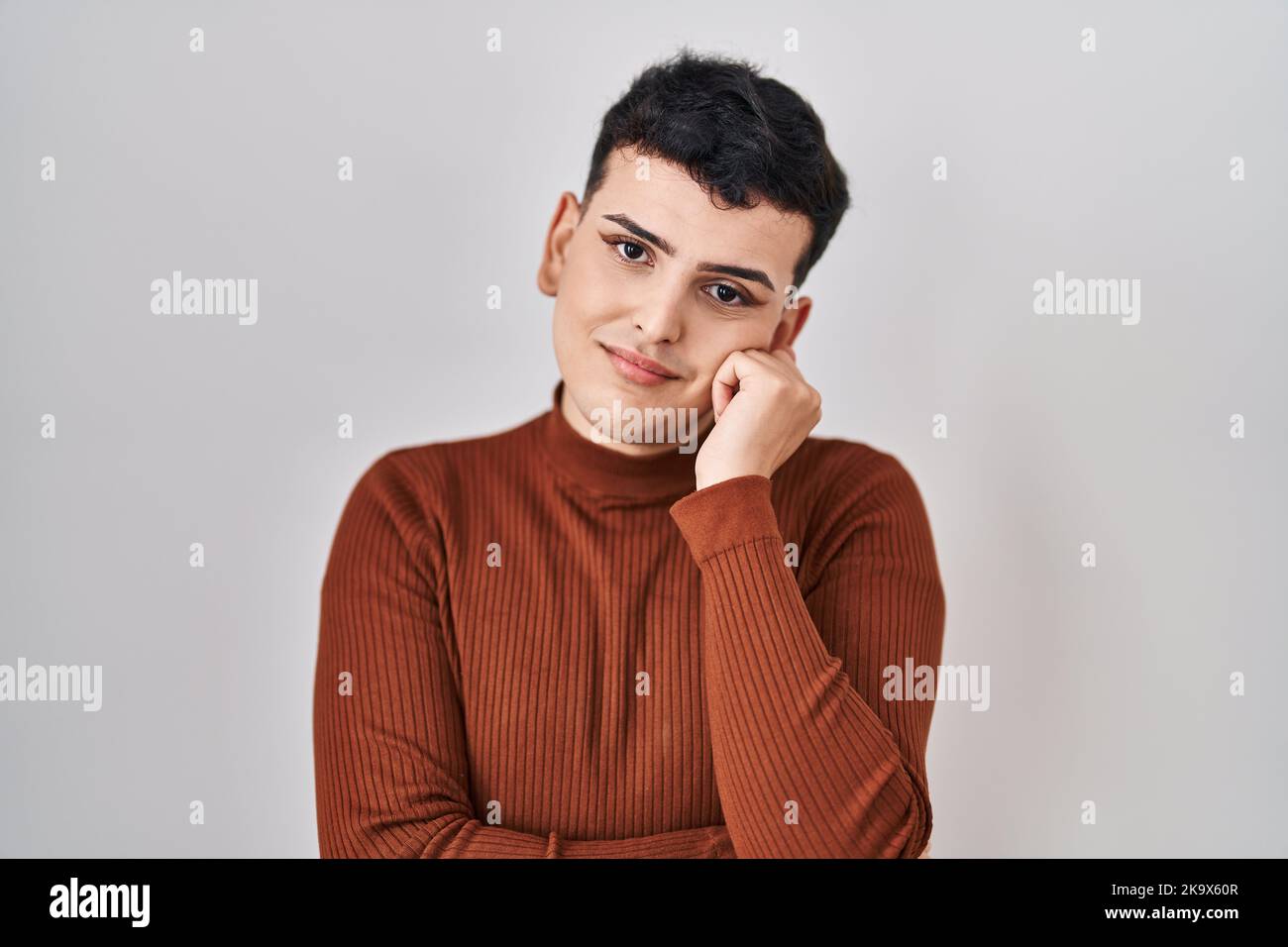 Non binary person wearing make up standing over isolated background ...