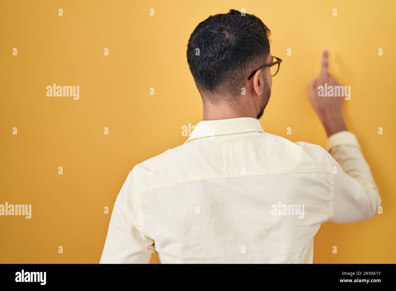 Hispanic young man wearing business clothes and glasses posing ...