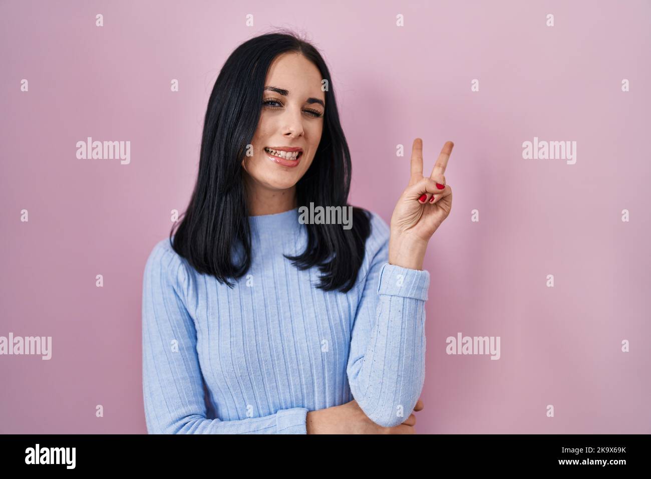 Hispanic woman standing over pink background smiling with happy face ...
