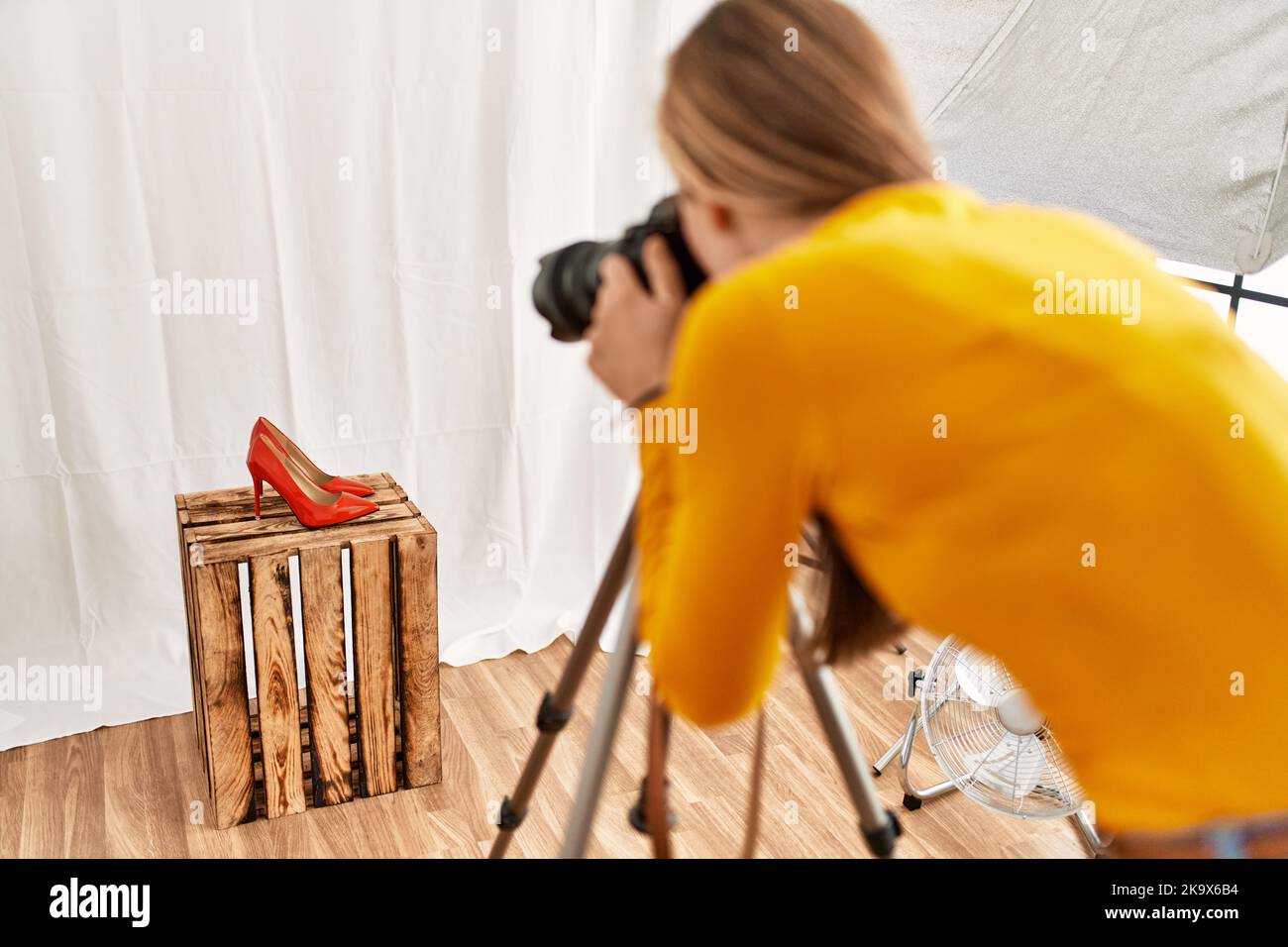 Young caucasian woman photographer making photo to high heel shoe at ...