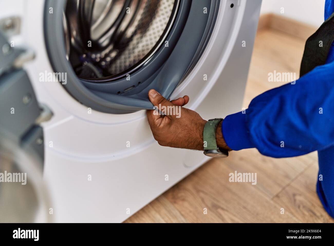 Young arab man wearing technician uniform repairing washing machine at ...