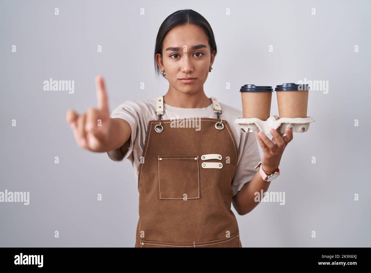 Young hispanic woman wearing professional waitress apron holding coffee ...