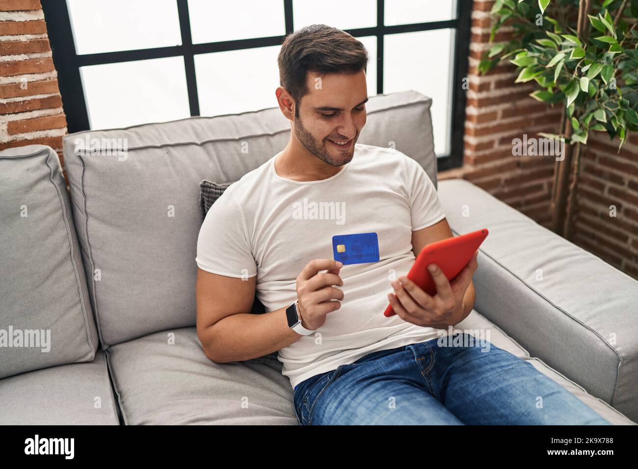 Young hispanic man using touchpad and credit card at home Stock Photo ...