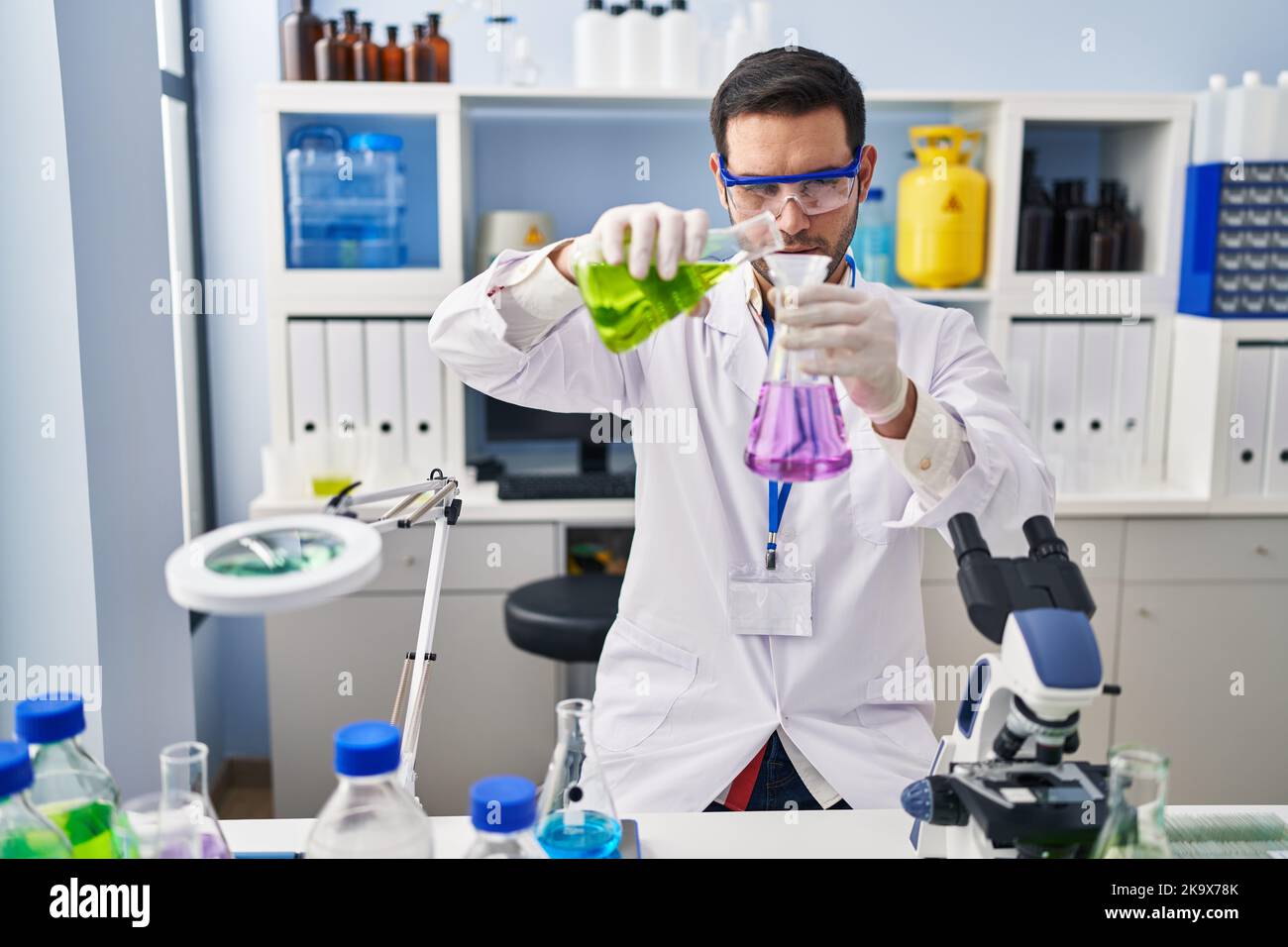 Young hispanic man scientist measuring liquid at laboratory Stock Photo ...