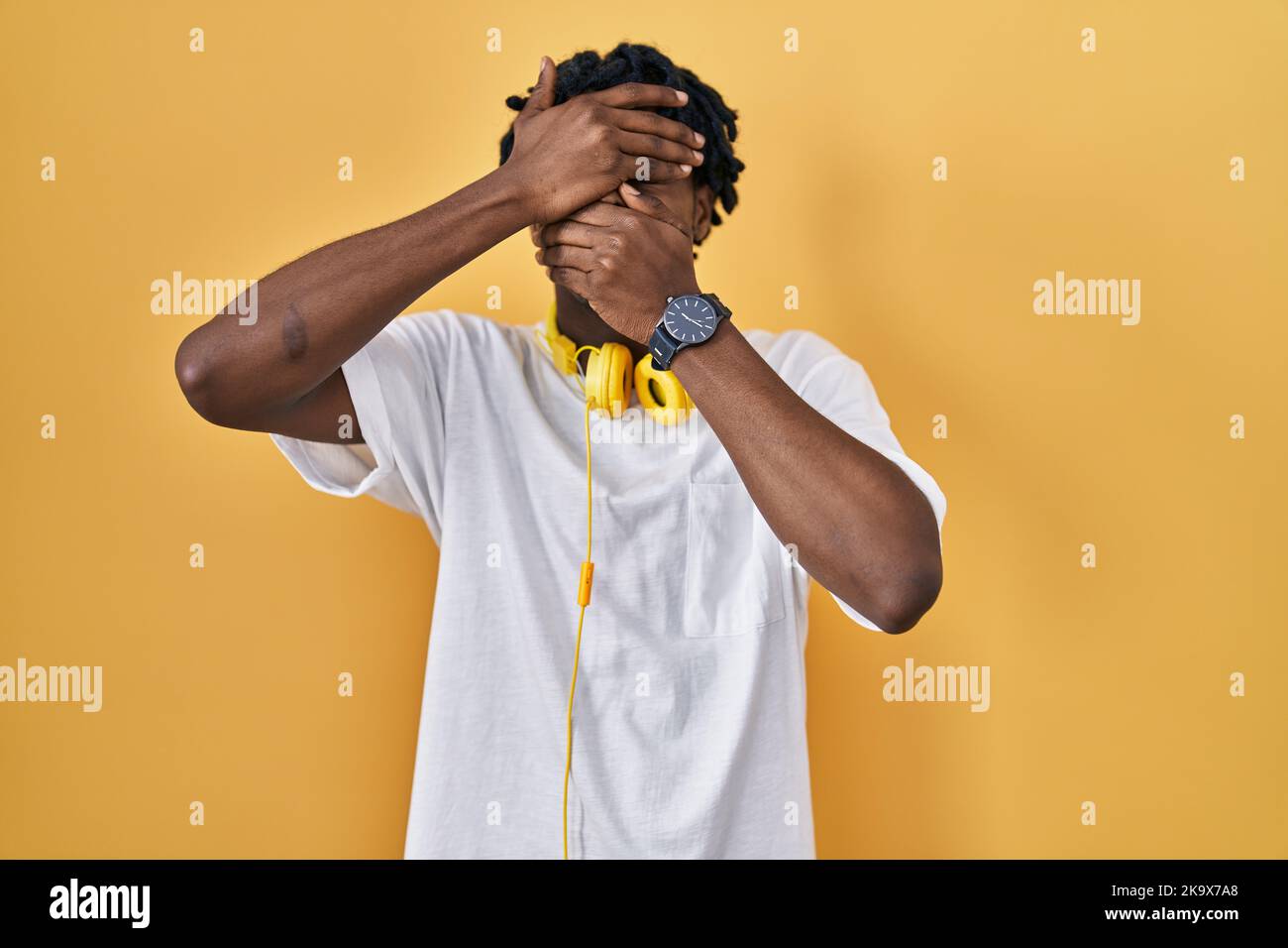 Young african man with dreadlocks standing over yellow background ...