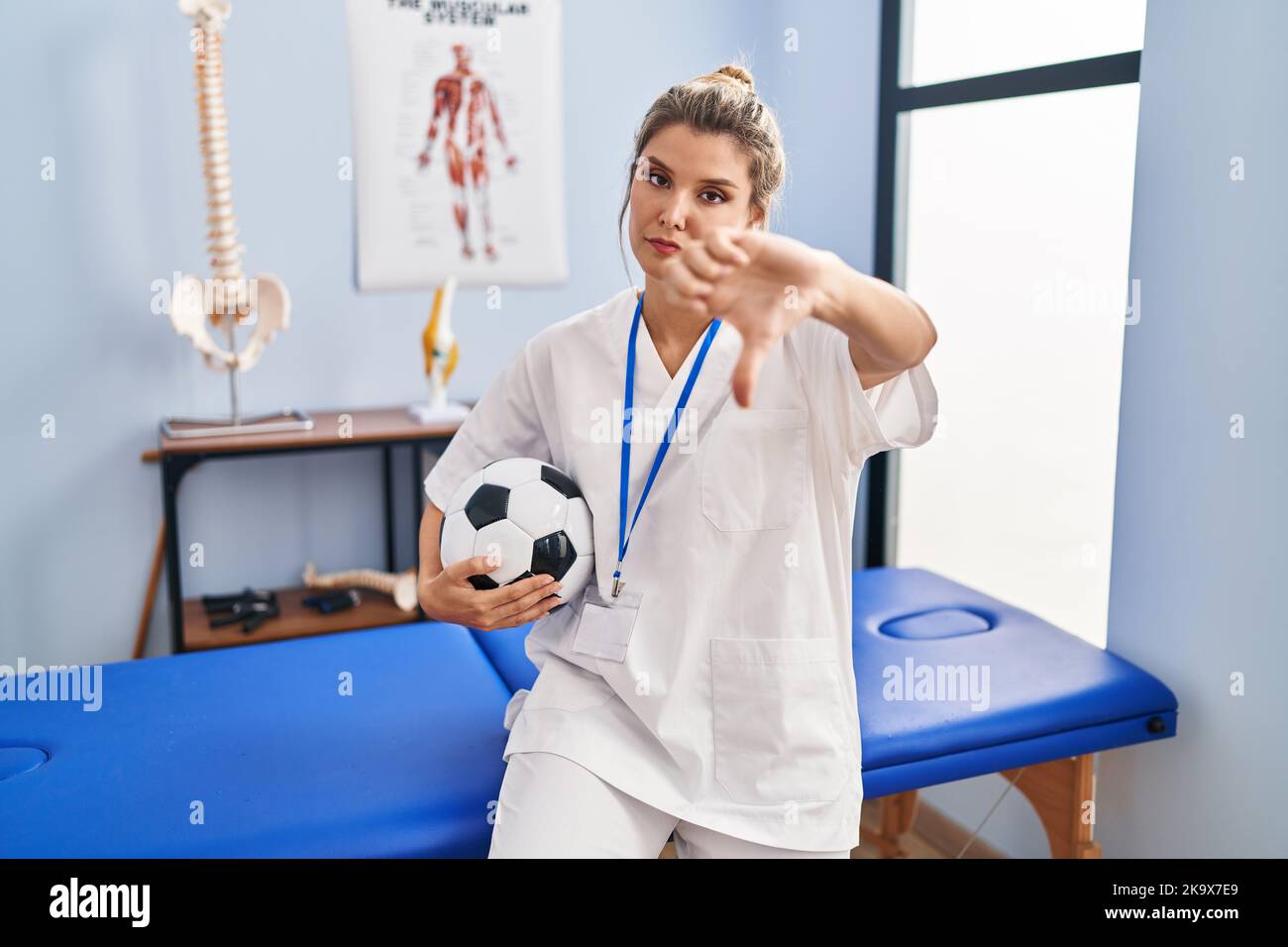 Young woman working at football therapy clinic with angry face ...