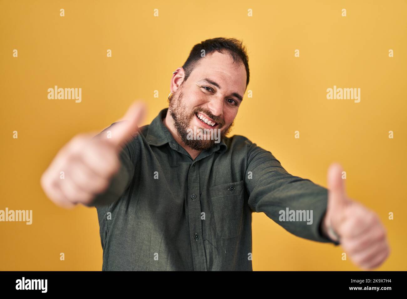 Plus size hispanic man with beard standing over yellow background ...