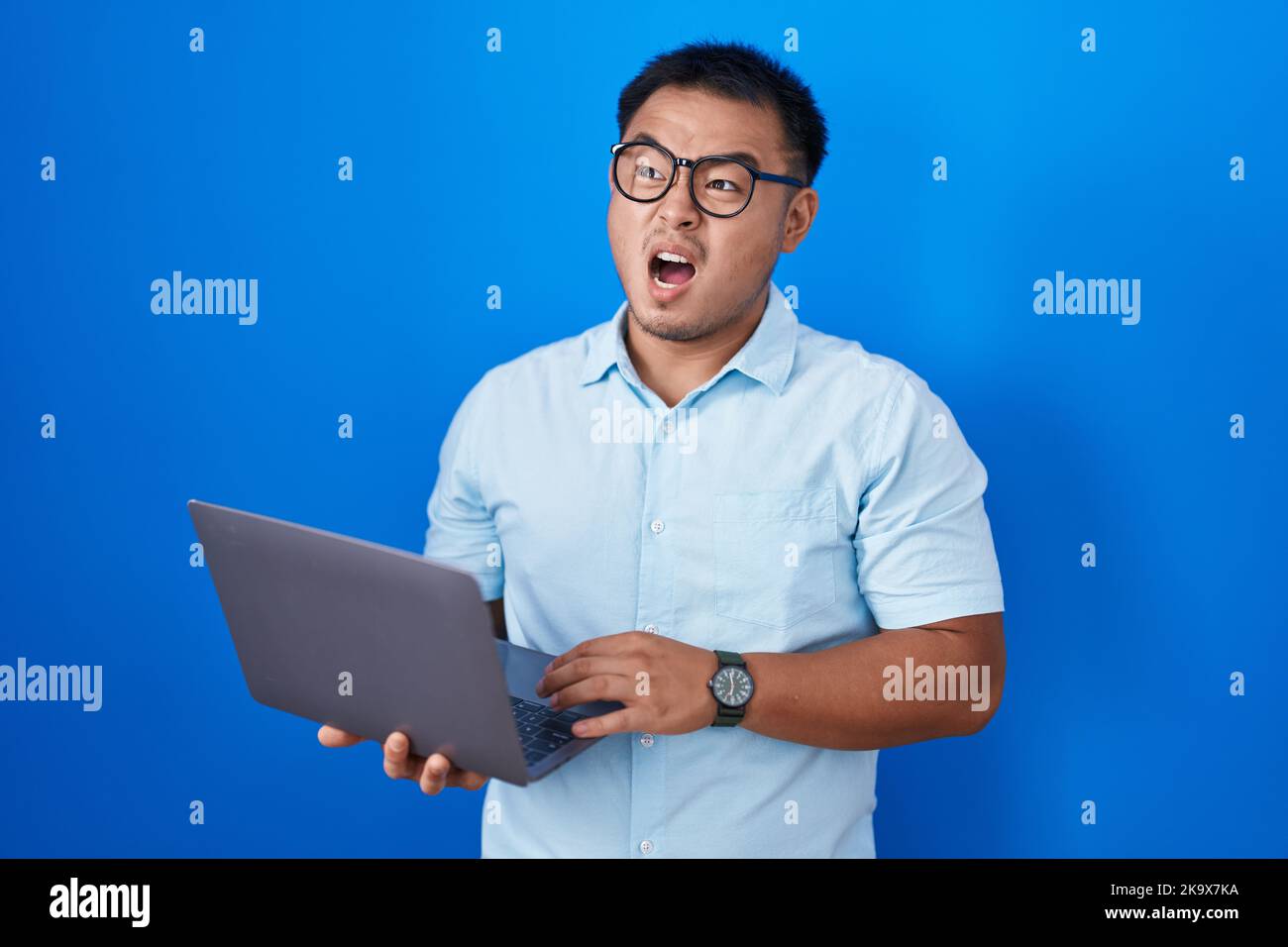 Chinese young man using computer laptop angry and mad screaming ...
