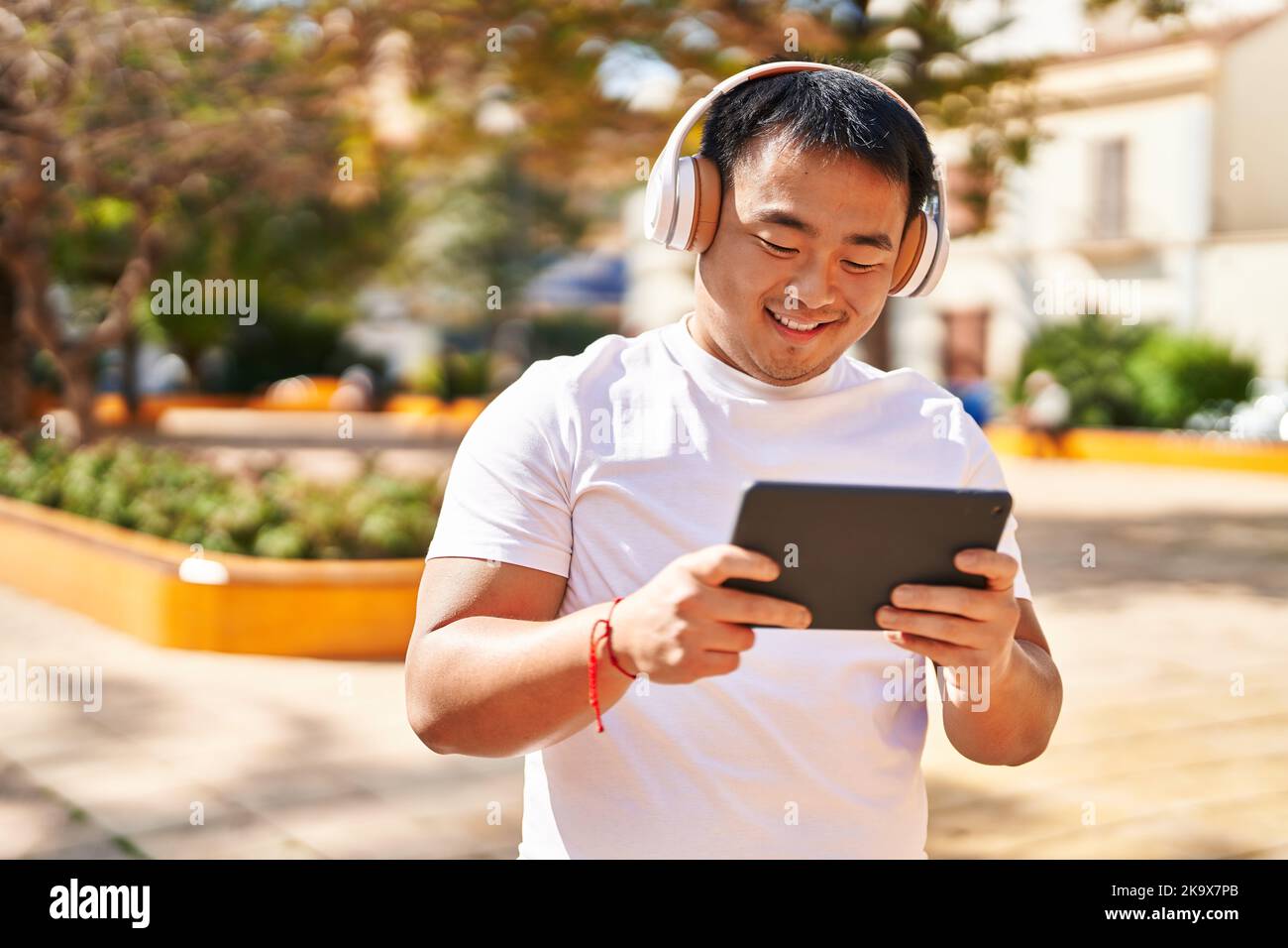 Young chinese man smiling confident watching video at park Stock Photo ...