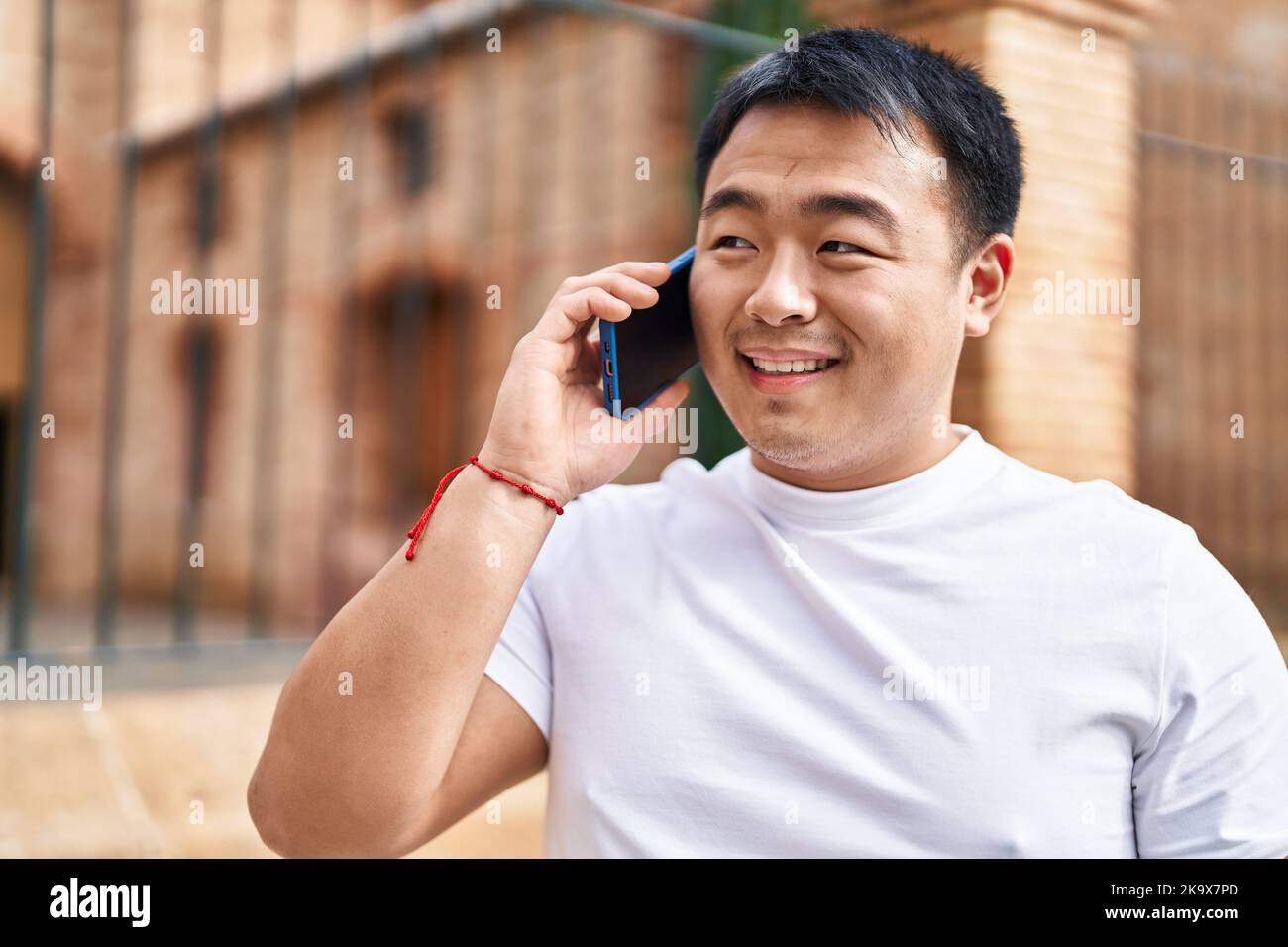 Young chinese man smiling confident talking on the smartphone at street ...