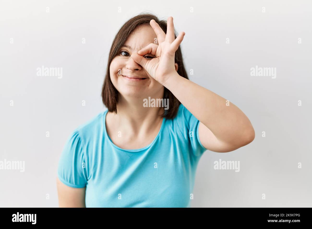 Young down syndrome woman standing over isolated background doing ok ...