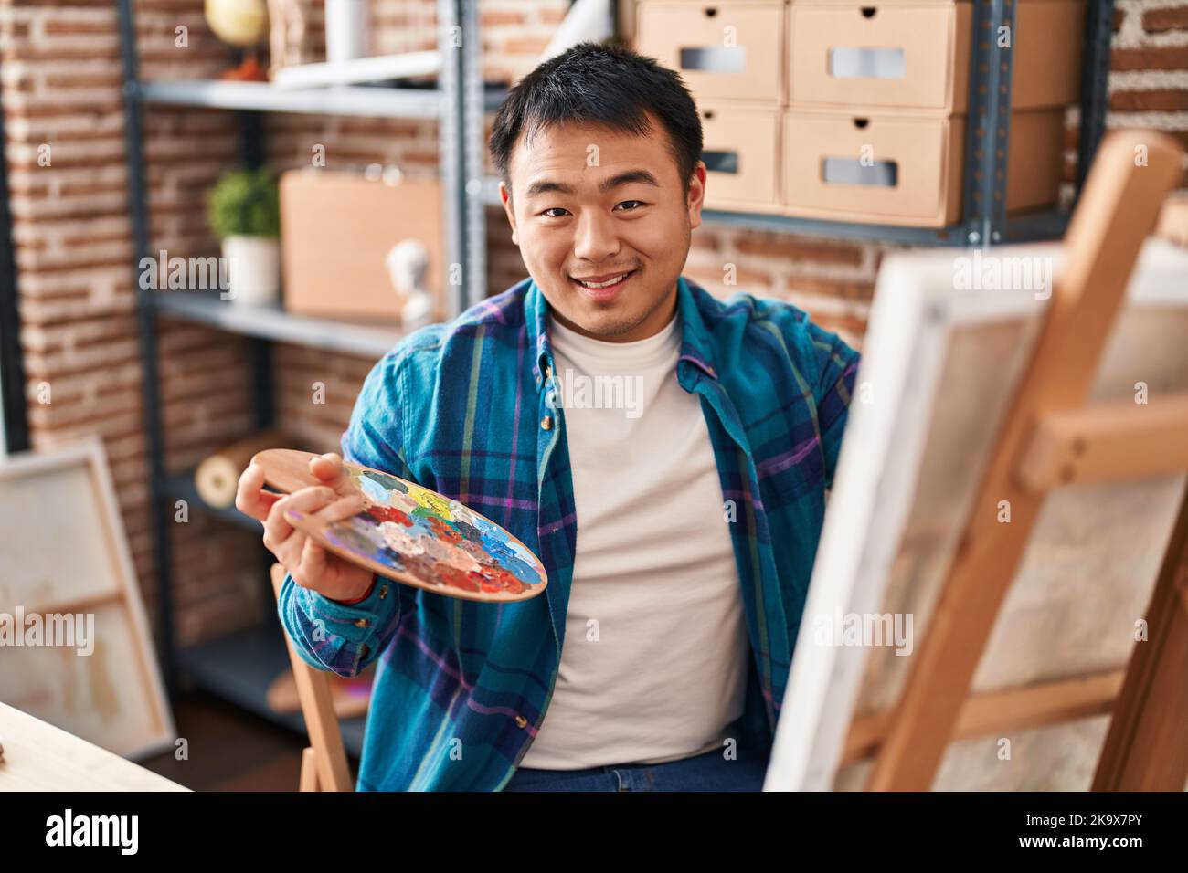 Young chinese man artist drawing on canvas at art studio Stock Photo ...