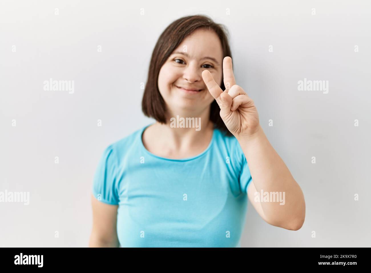Young down syndrome woman standing over isolated background smiling ...