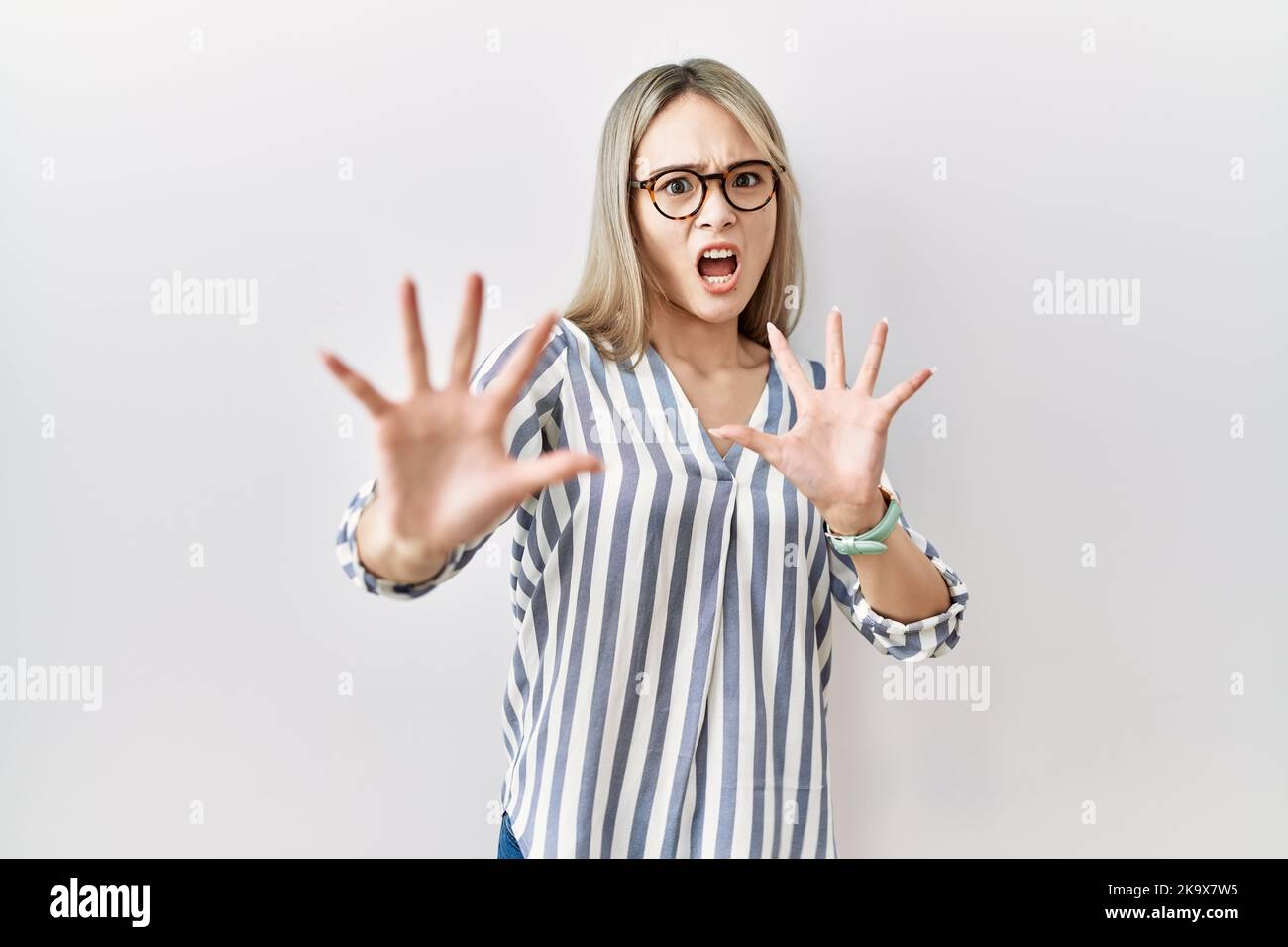 Asian young woman wearing casual clothes and glasses afraid and ...