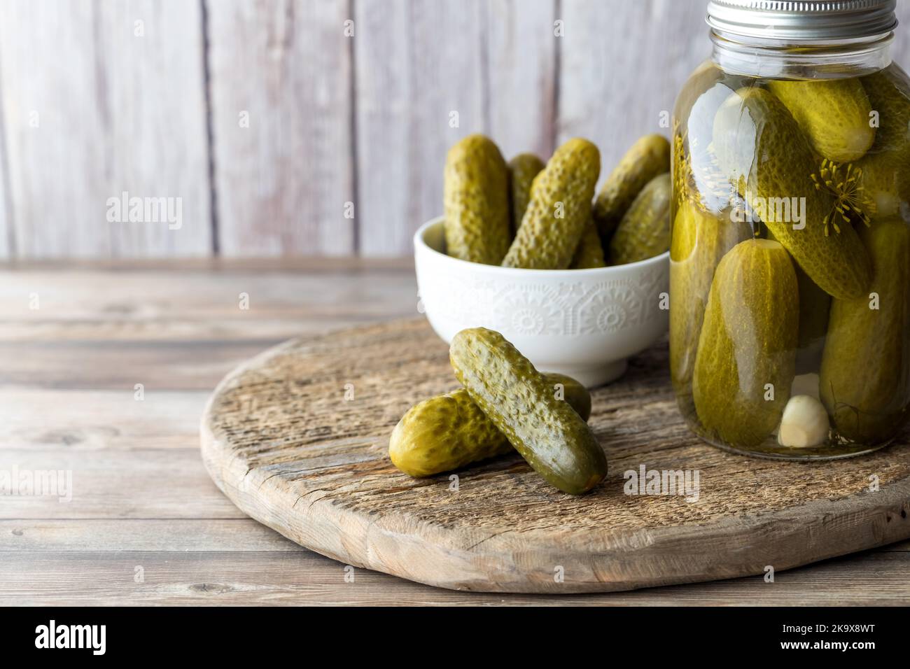 A jar of homemade dill pickles with a bowl full and pickles in front ...