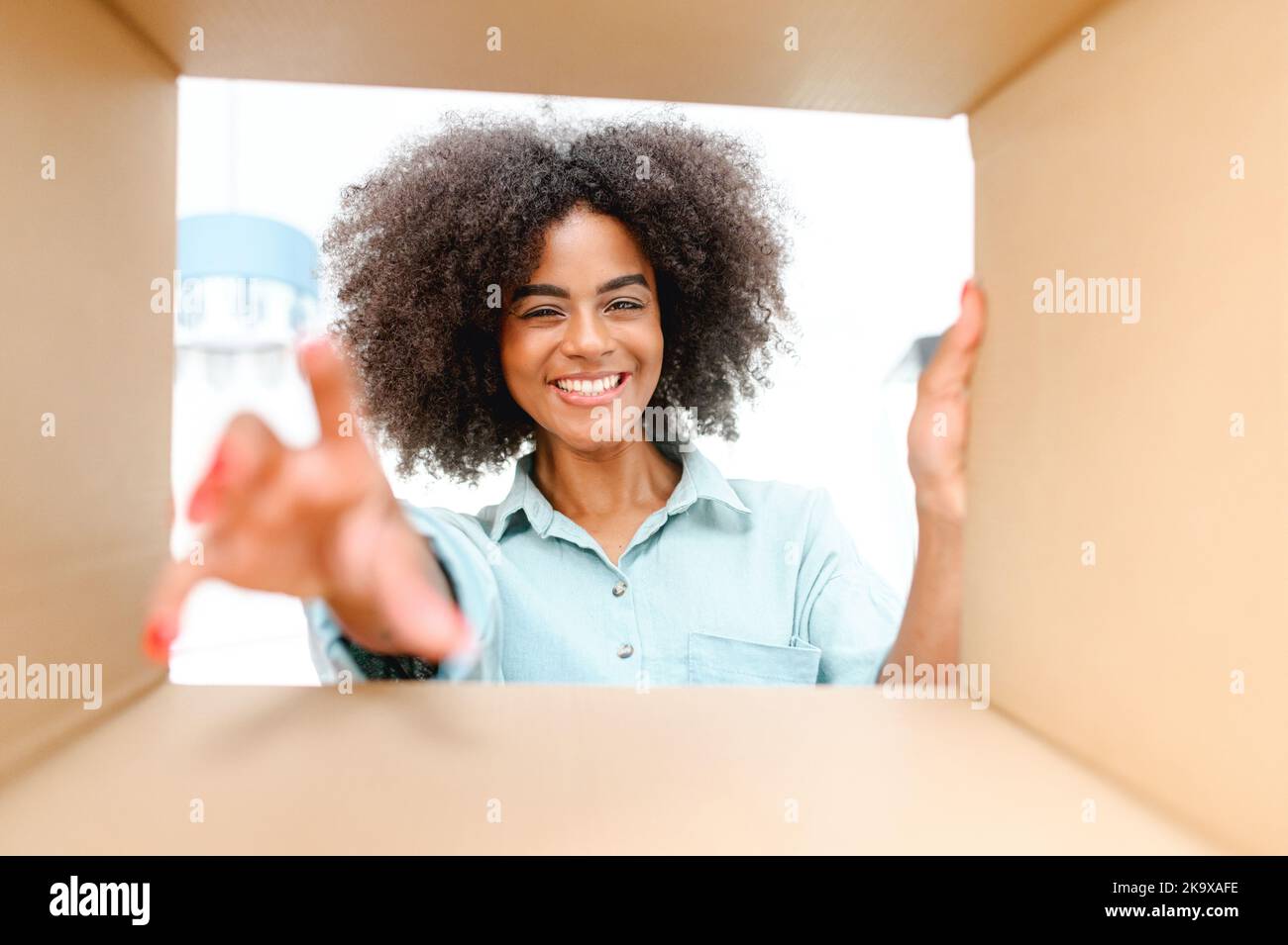 Camera inside delivery box, happy African woman taking out parcel from ...