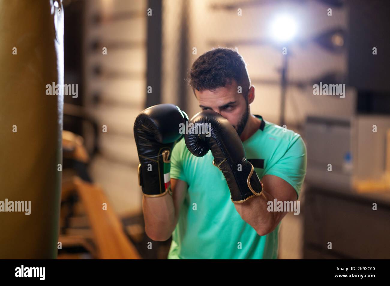Muscular man with boxing gloves hitting a punching bag in a fitness ...