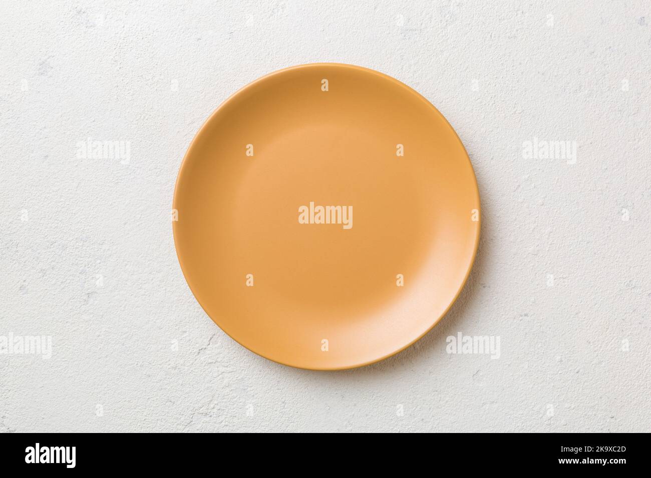 Top view of empty orange plate on cement background. Empty space for ...