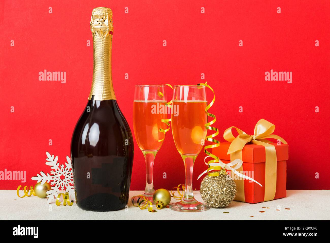 Champagne bottle with confetti, glasses and christmas decor on colored ...