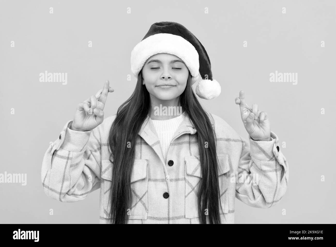 dreamy kid in santa claus hat crossed fingers for luck on yellow ...