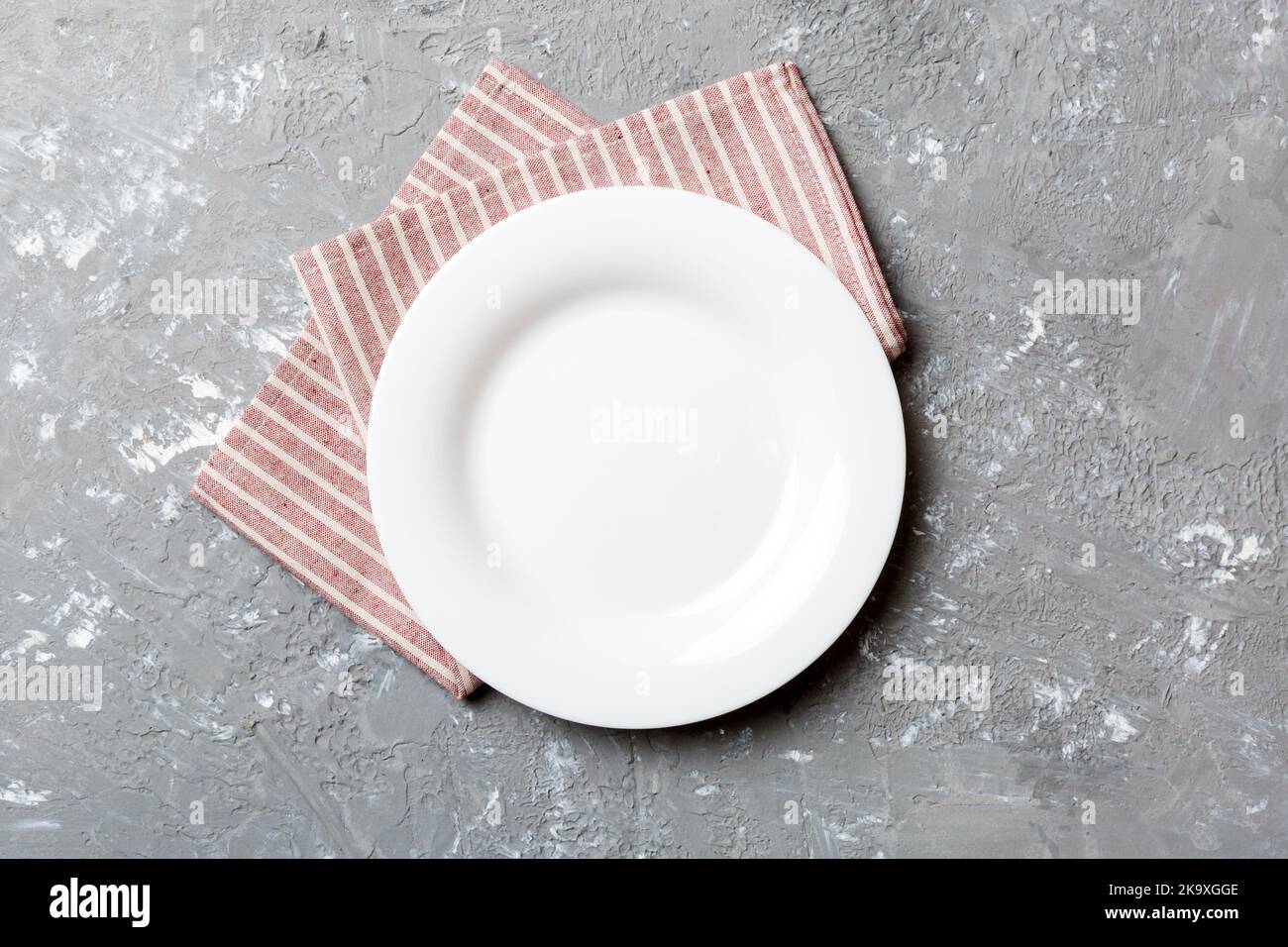 Top view on colored background empty round white plate on tablecloth ...
