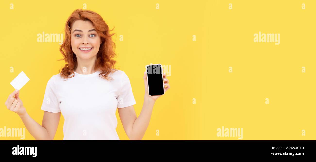 excited young lady isolated overyellow background using mobile phone holding credit card. Woman ...