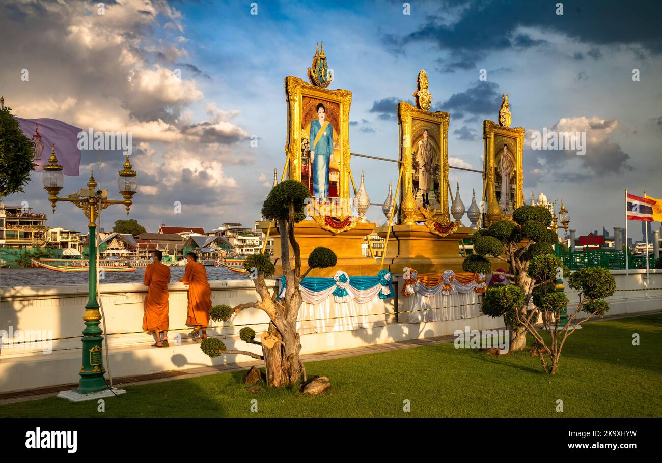 Two Buddhist monks stand to watch the Chao Phraya River next to ...