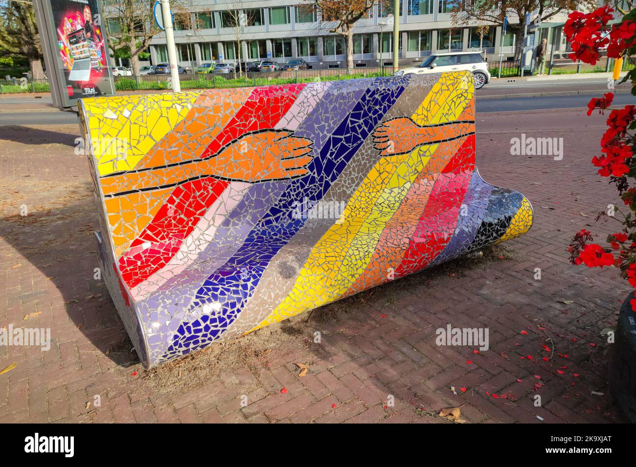 Bench in mosaic pattern on which two hands reach for each other as a ...