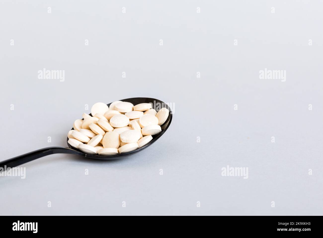Heap of white pills on colored background. Tablets scattered on a table ...