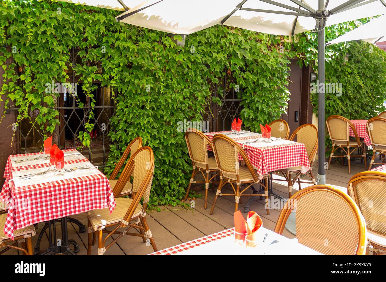 Sunny outdoor restaurant scenery with tables and chairs in front of a ...