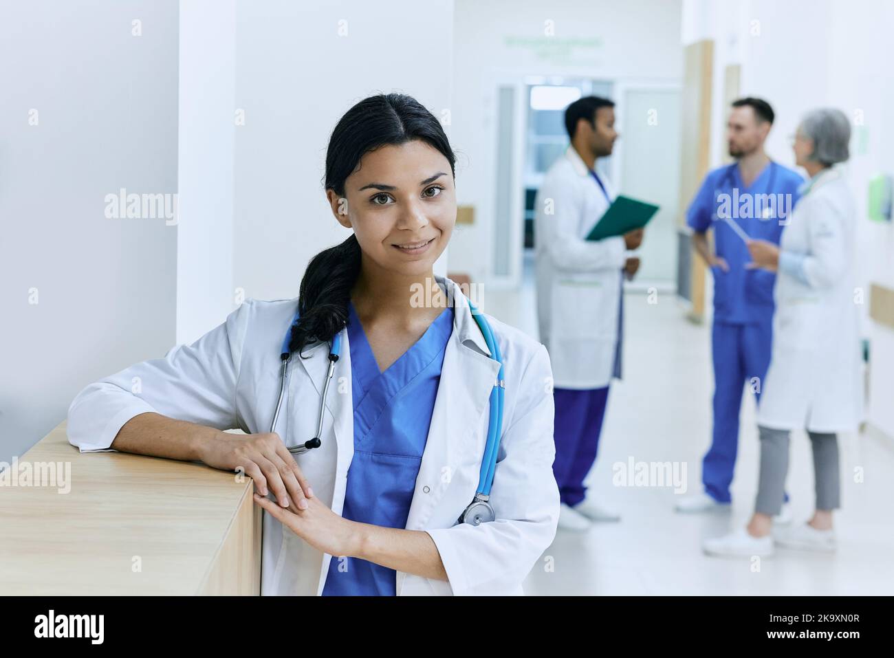 Positive Asian female physician standing with stethoscope in hallway ...