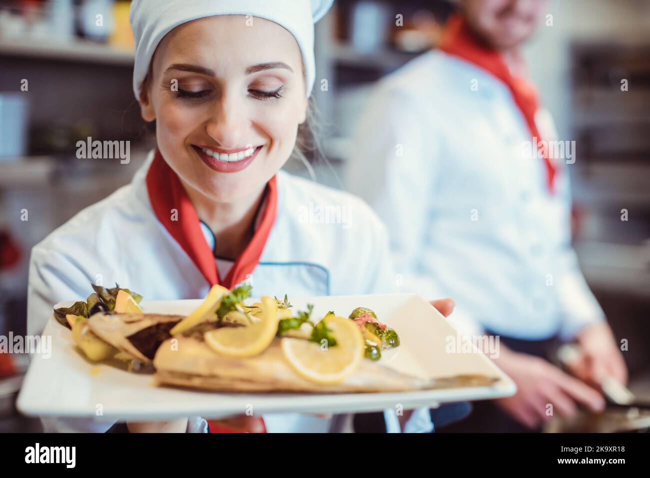 Chef in uniform in a restaurant kitchen presenting her food Stock Photo ...