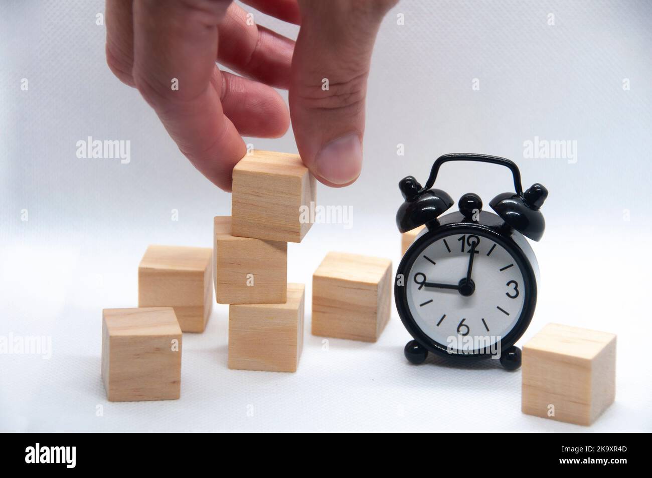 Blank wooden cubes and black alarm clock on white background with ...