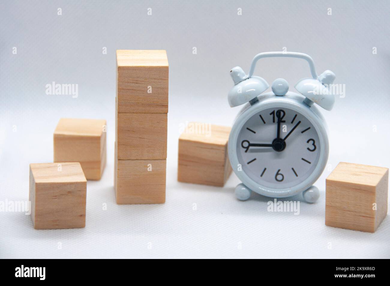 Blank wooden cubes and white alarm clock on white background with ...