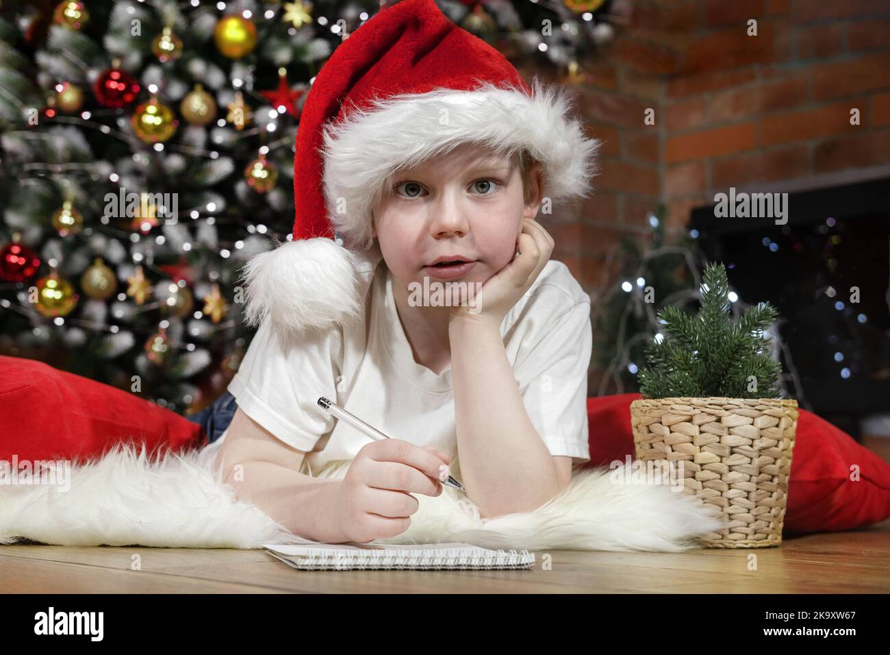 Happy Christmas kids. Boy child in Santa Claus hat writes a letter to ...