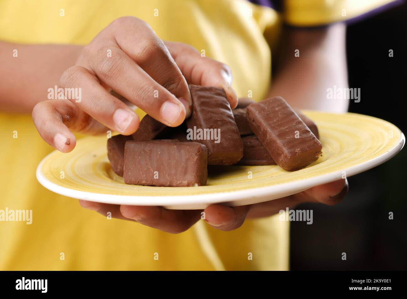 child boy hand pick dark chocolate on a plate Stock Photo - Alamy