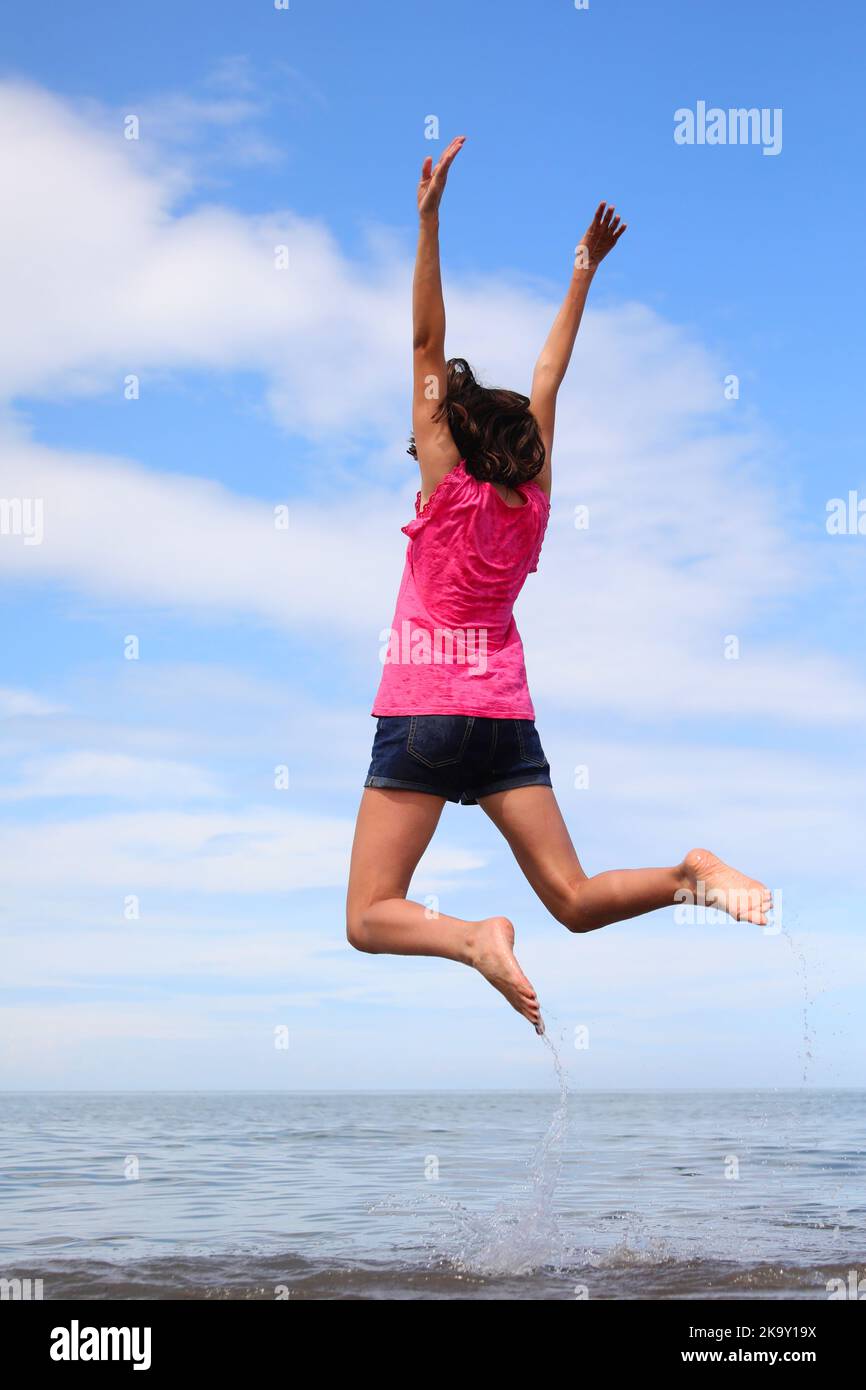 contented girl jumping and rejoicing happy by the sea in summer Stock ...