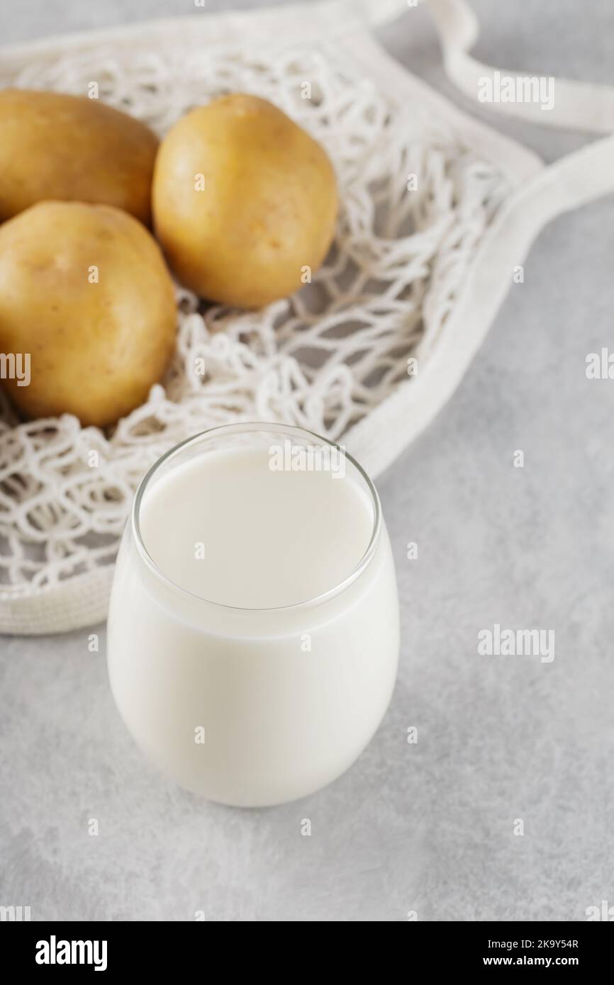 Potato milk and raw potatoes in a mesh bag. Plant based milk replacer ...