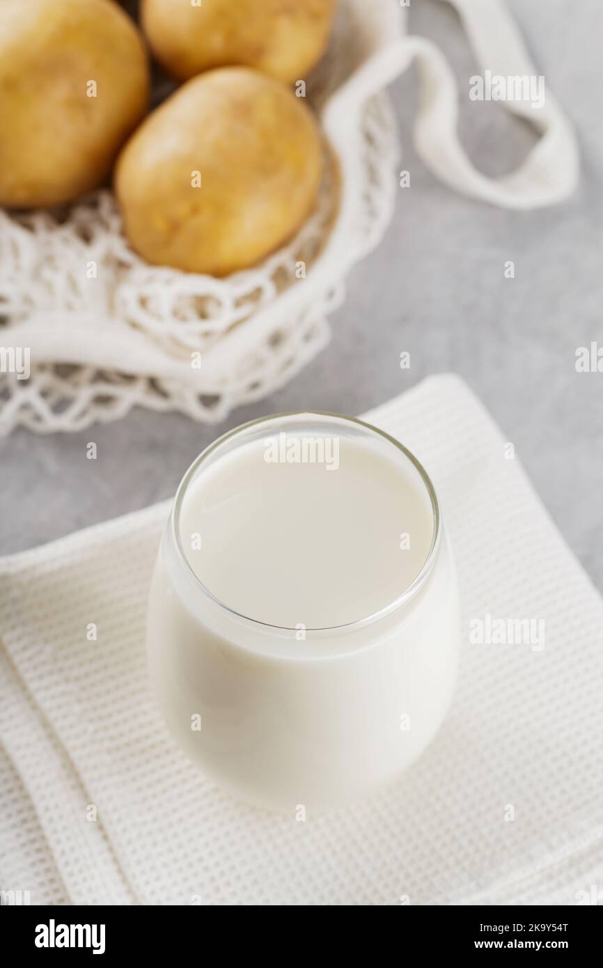 Potato milk and raw potatoes in a mesh bag. Plant based milk replacer ...
