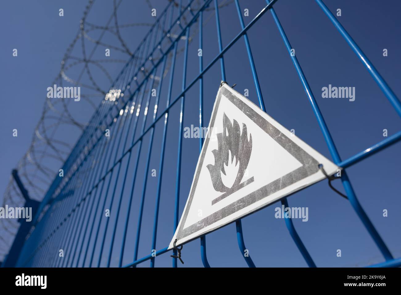 An explosion hazard sign hanging on a fence around a gas installation ...