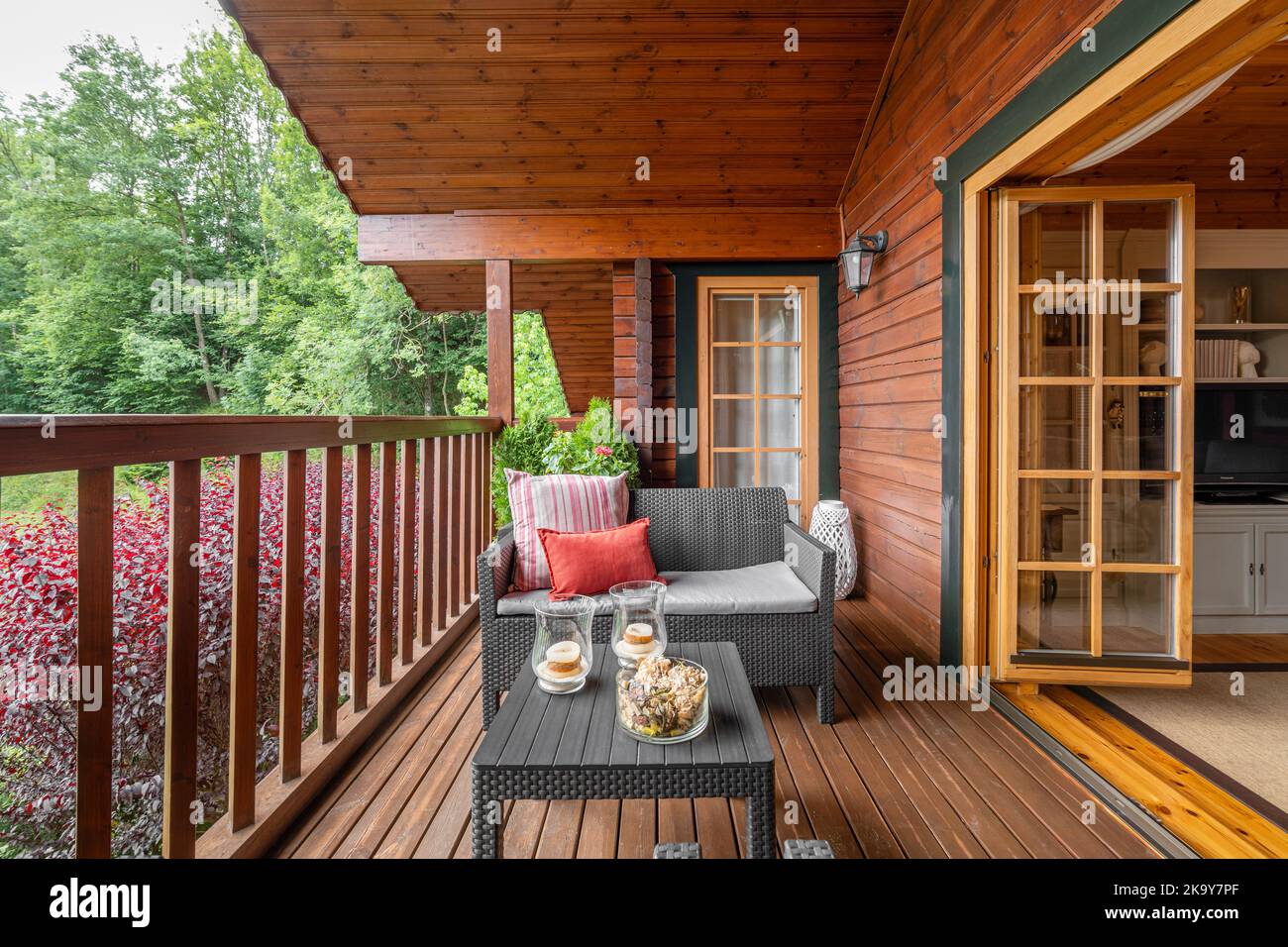 Cozy terrace with table and sofa at wooden cottage house surrounded by ...