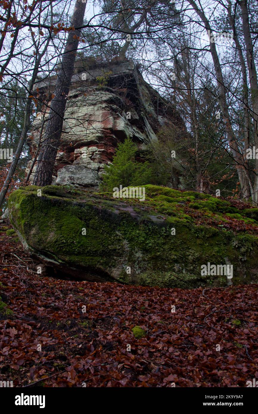 Rock covered in green moss in front of tall rock formation in the ...