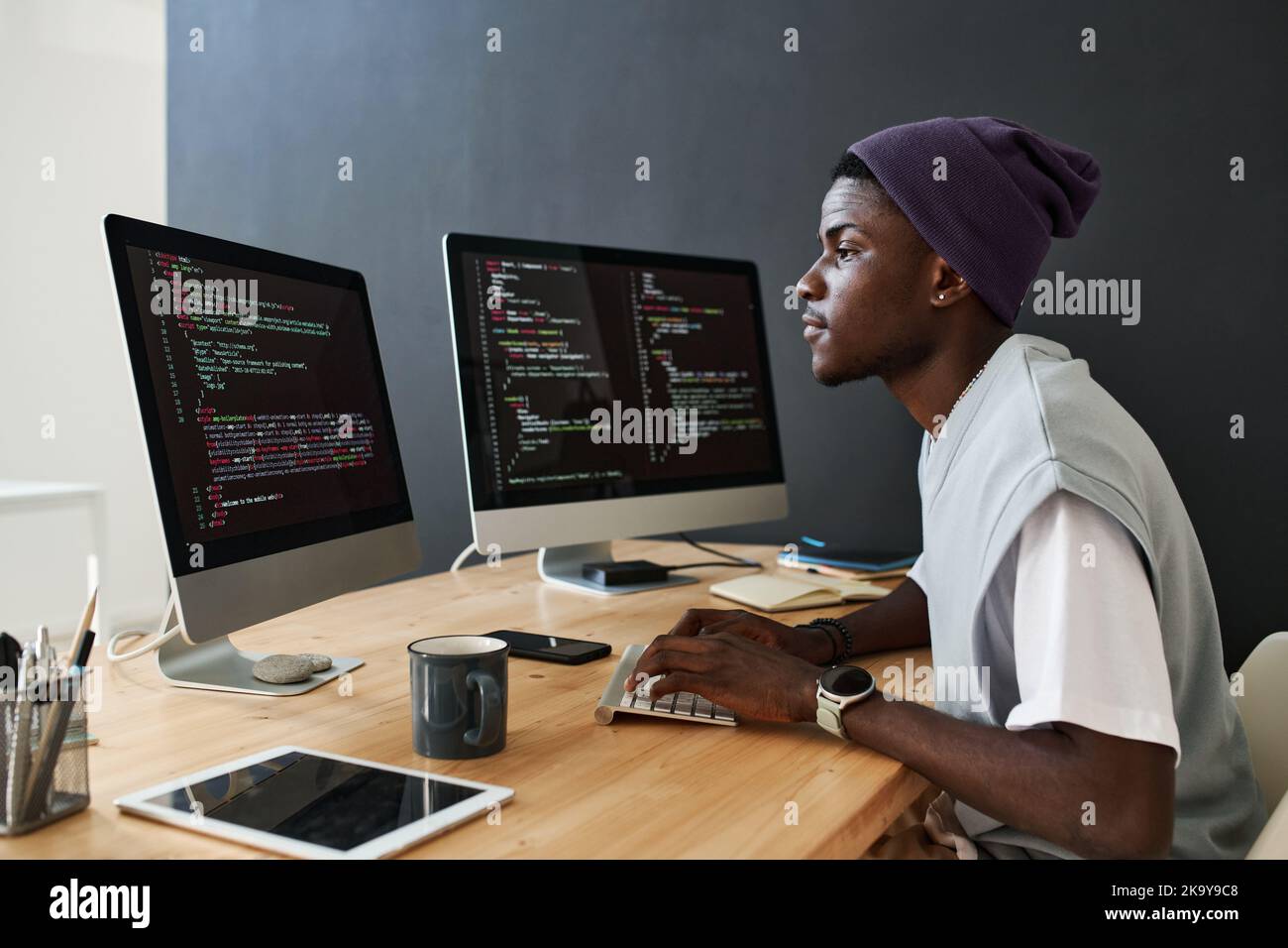 Young serious African American male programmer working over new software in front of computer ...