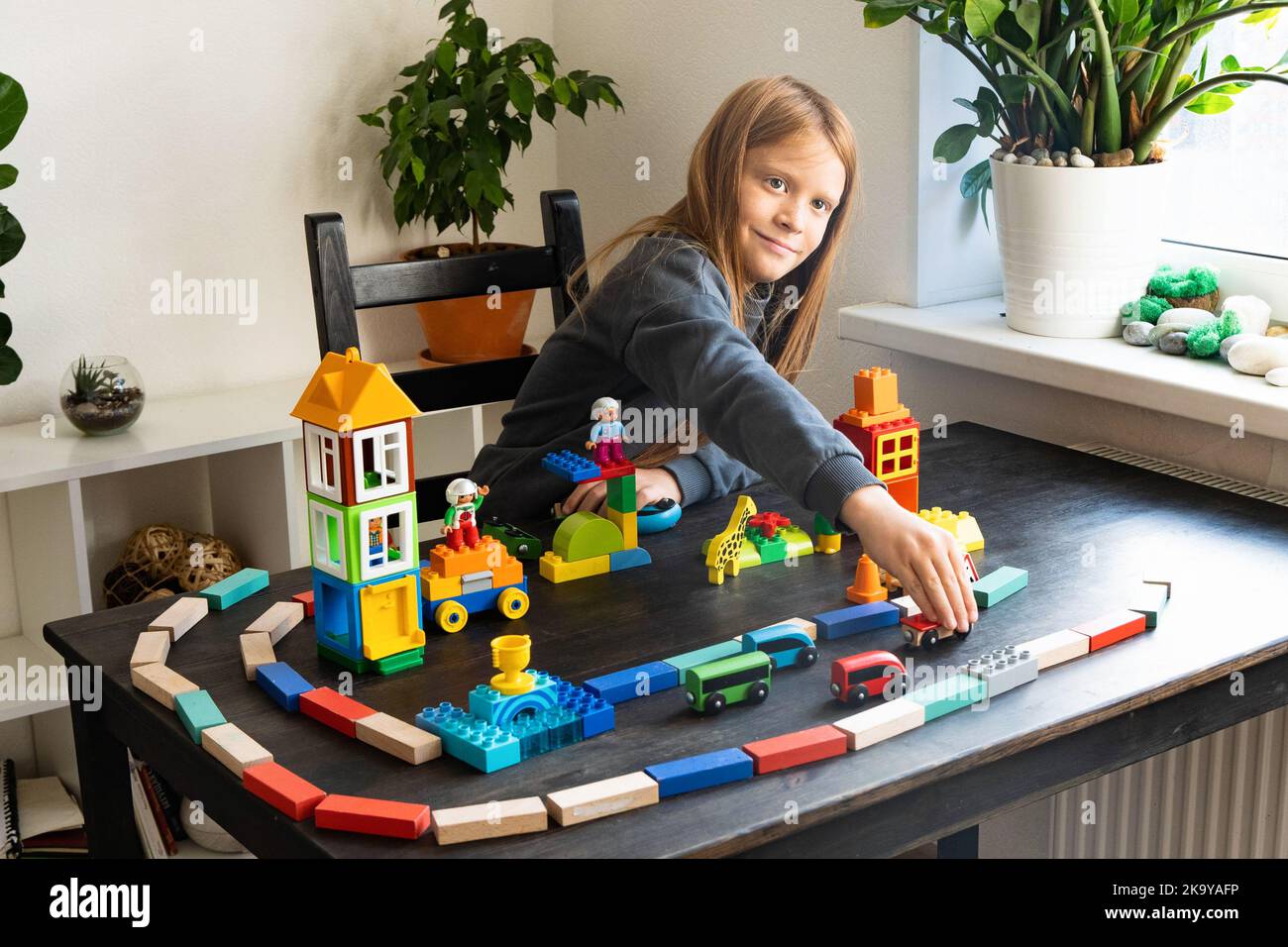 The boy of 8 years is playing cubes and blocks . He built a city and a ...