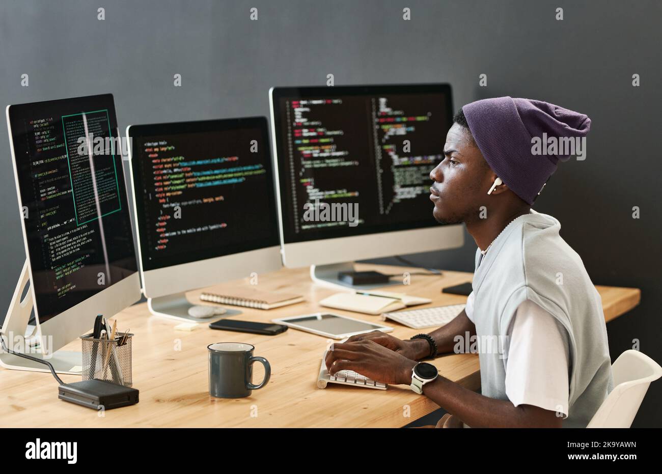 Young Serious It Engineer In Casualwear Looking At Coded Data On Computer Screens While Typing