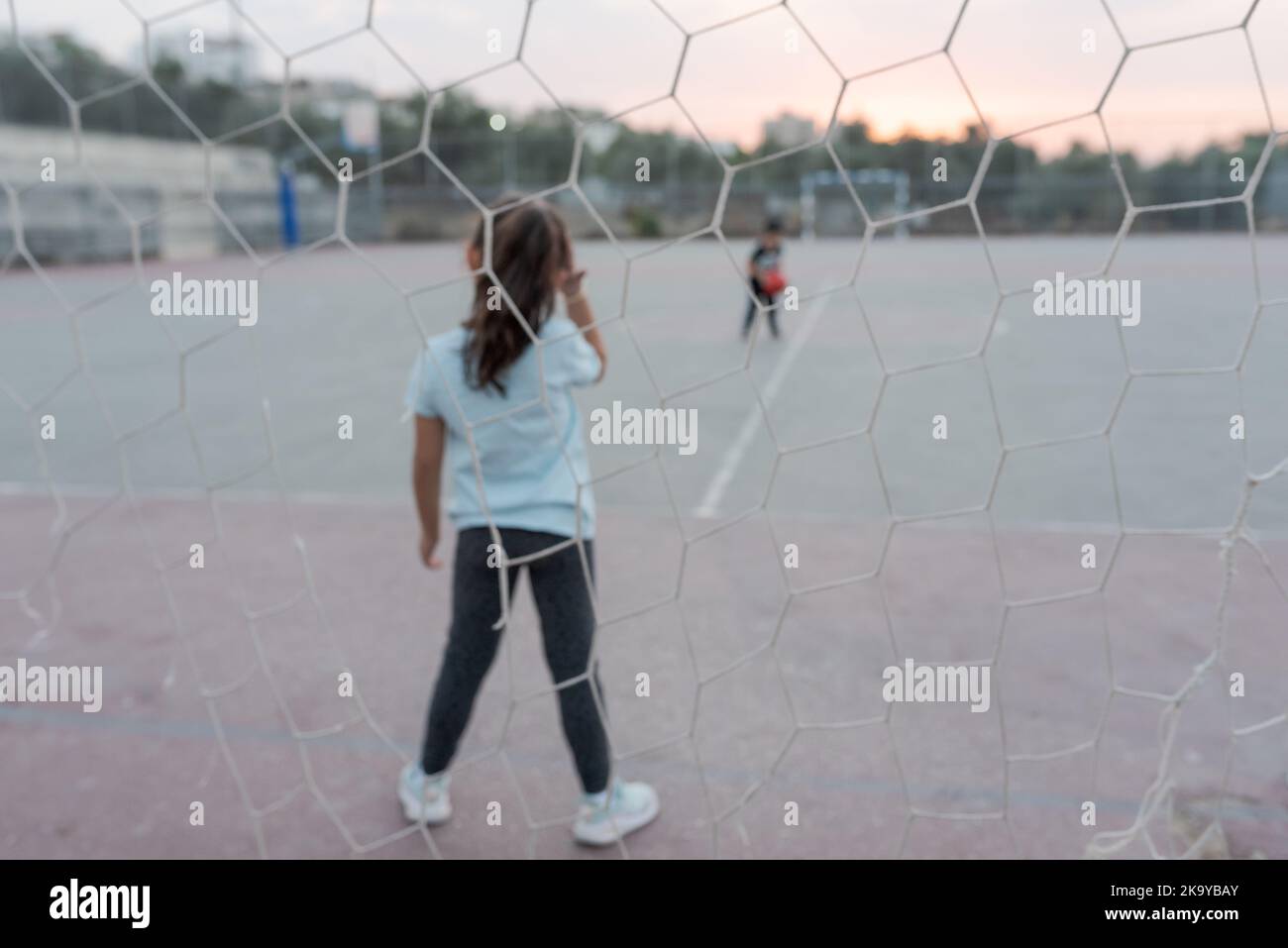 Blurred image. Back view of female child goalkeeper ready to catch a ...