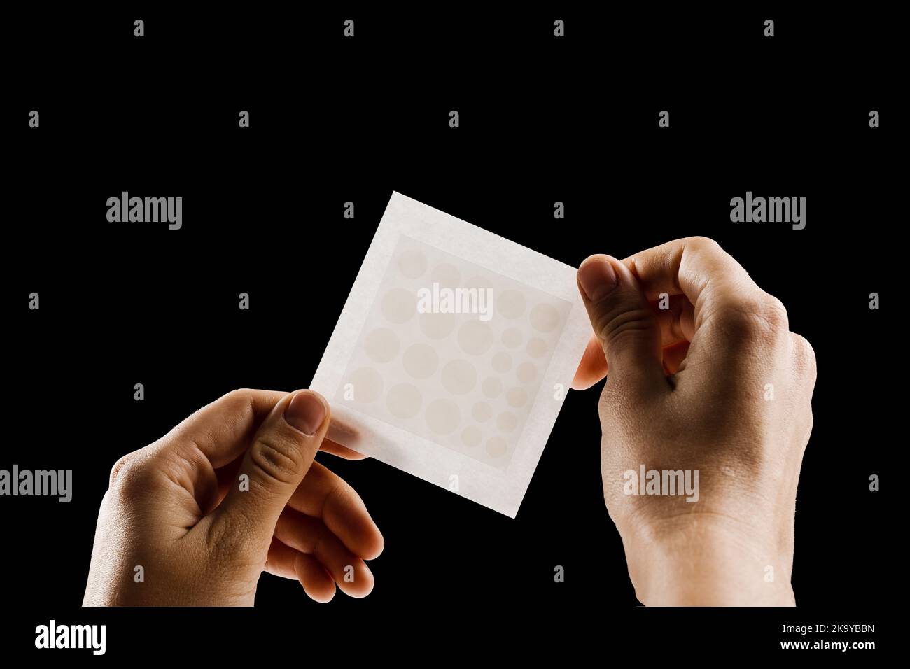 Set of round patches for acne in hands on black background. Close-up ...
