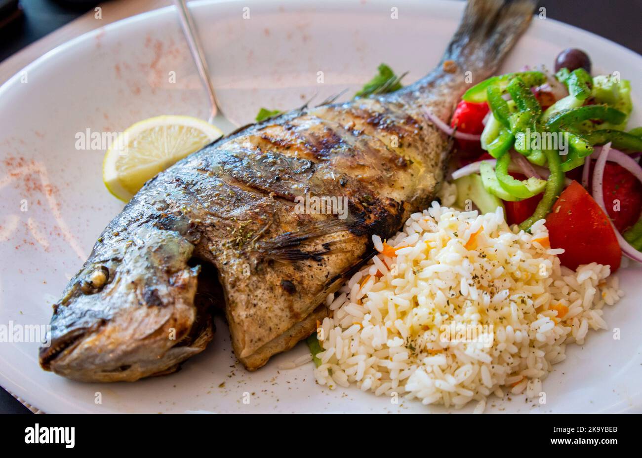 A whole grilled sea bream with rice and salad from a Greece local ...