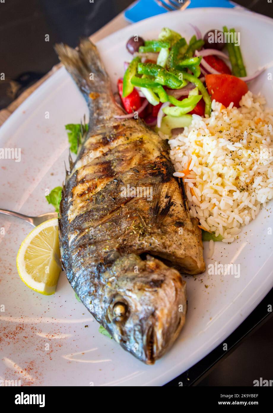 A whole grilled sea bream with rice and salad from a Greece local ...